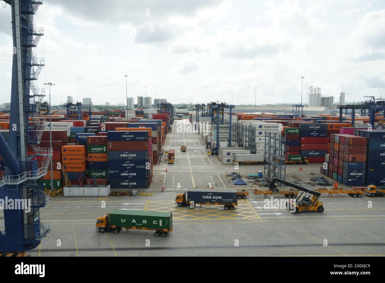 Container terminal with reach stacker, trucks and boxes from different ...