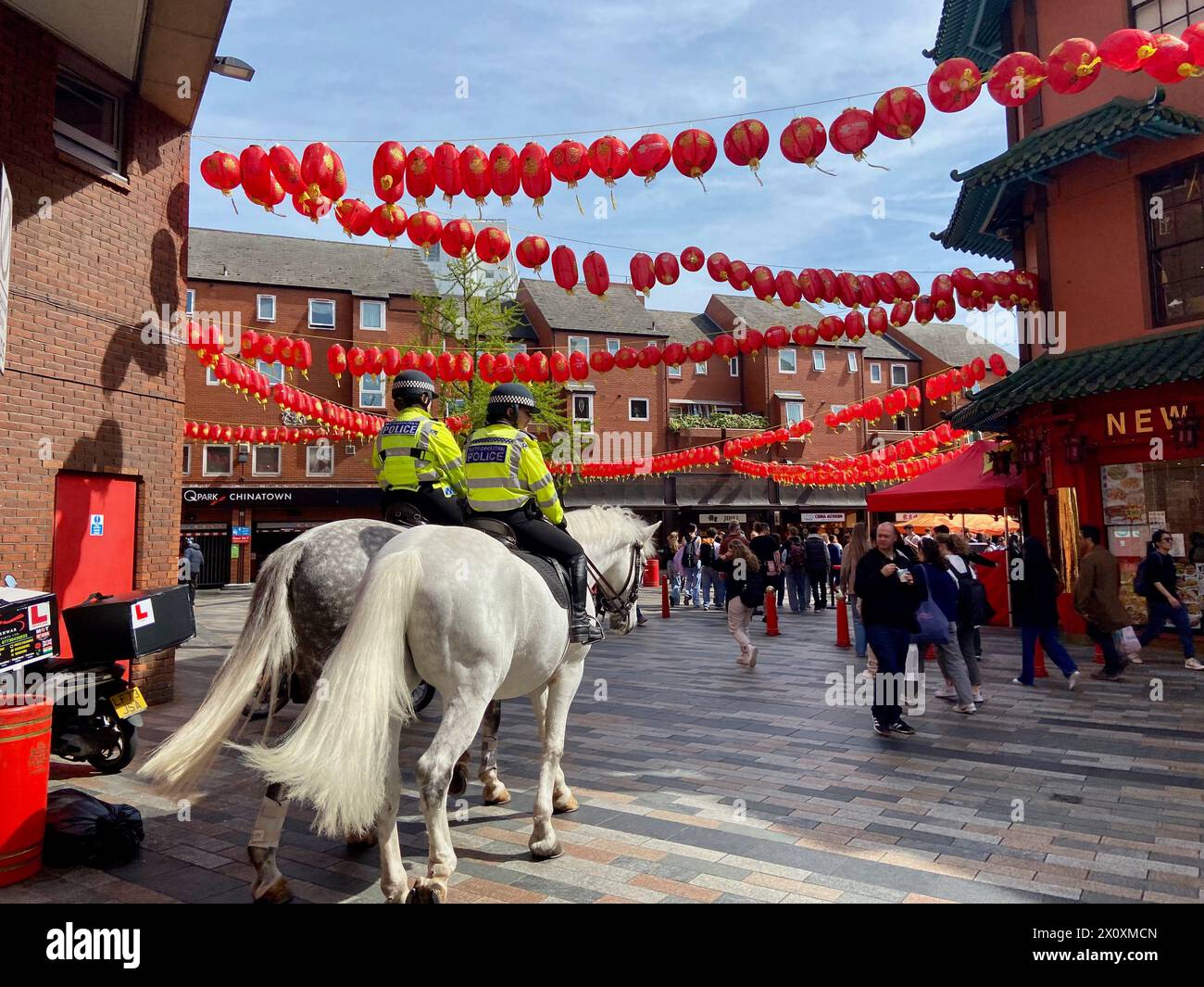 two mounted Met police officers riding horses through chinatown soho ...