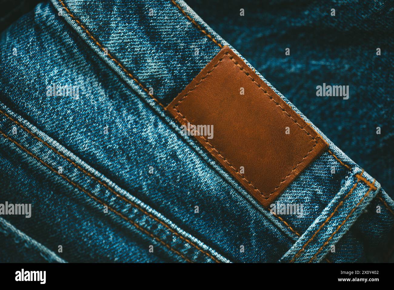 Blank brown leather empty jeans label sewed on a blue jeans denim ...