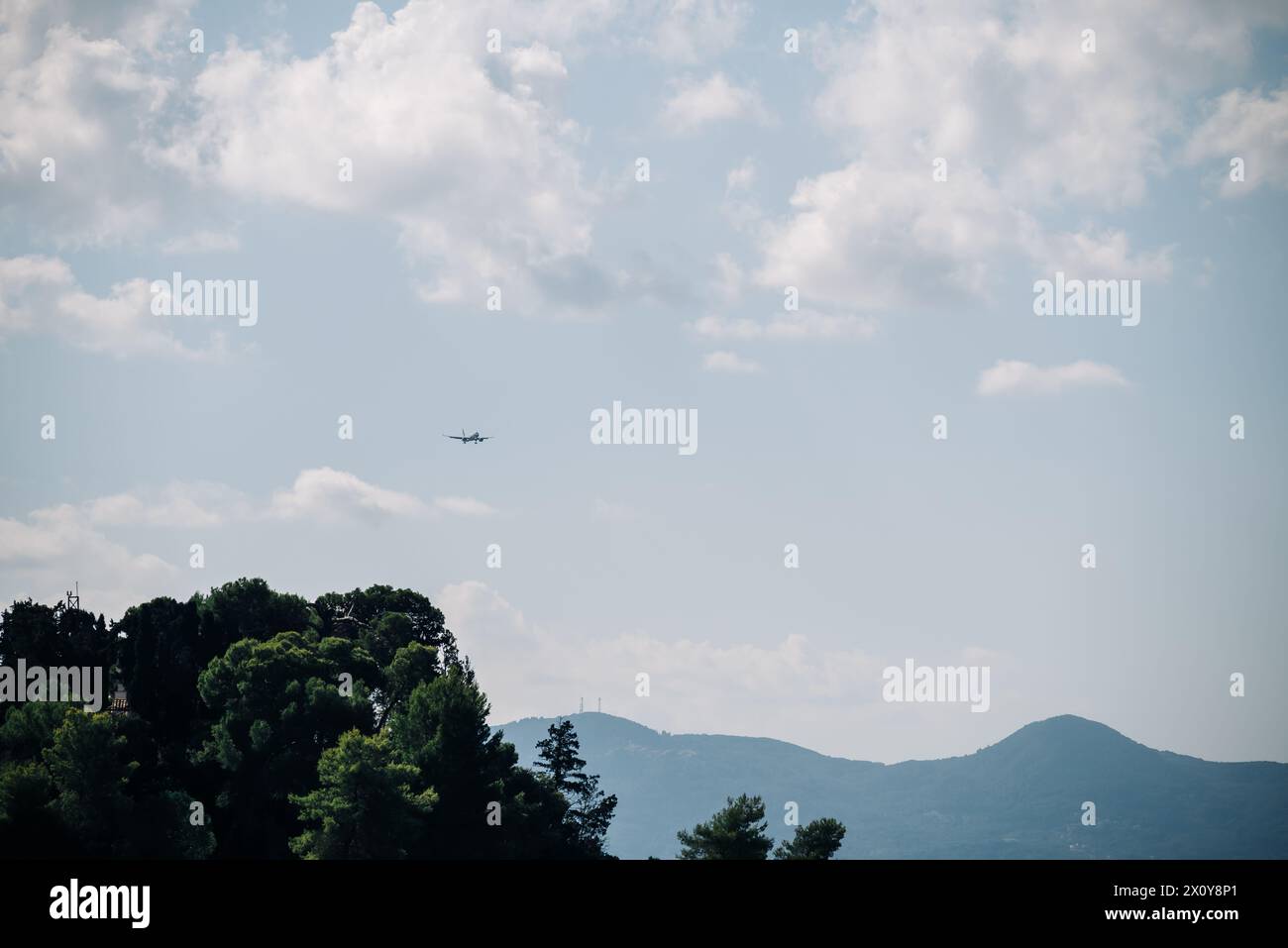 Plane soars over trees, mountains with clouds in sky Stock Photo - Alamy