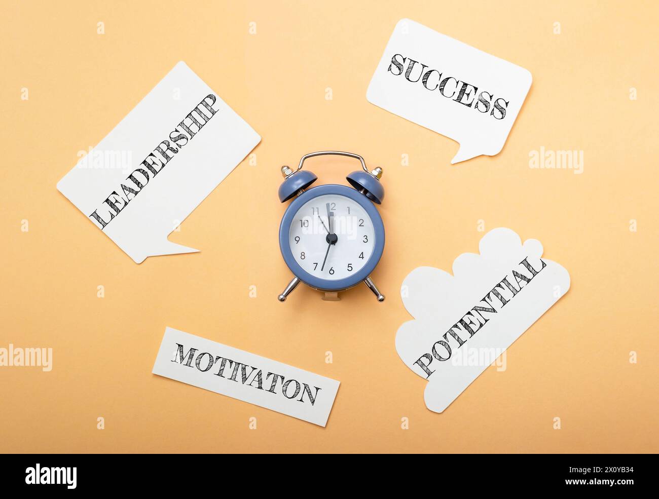 A blue alarm clock sits on a table with a bunch of paper cutouts around ...