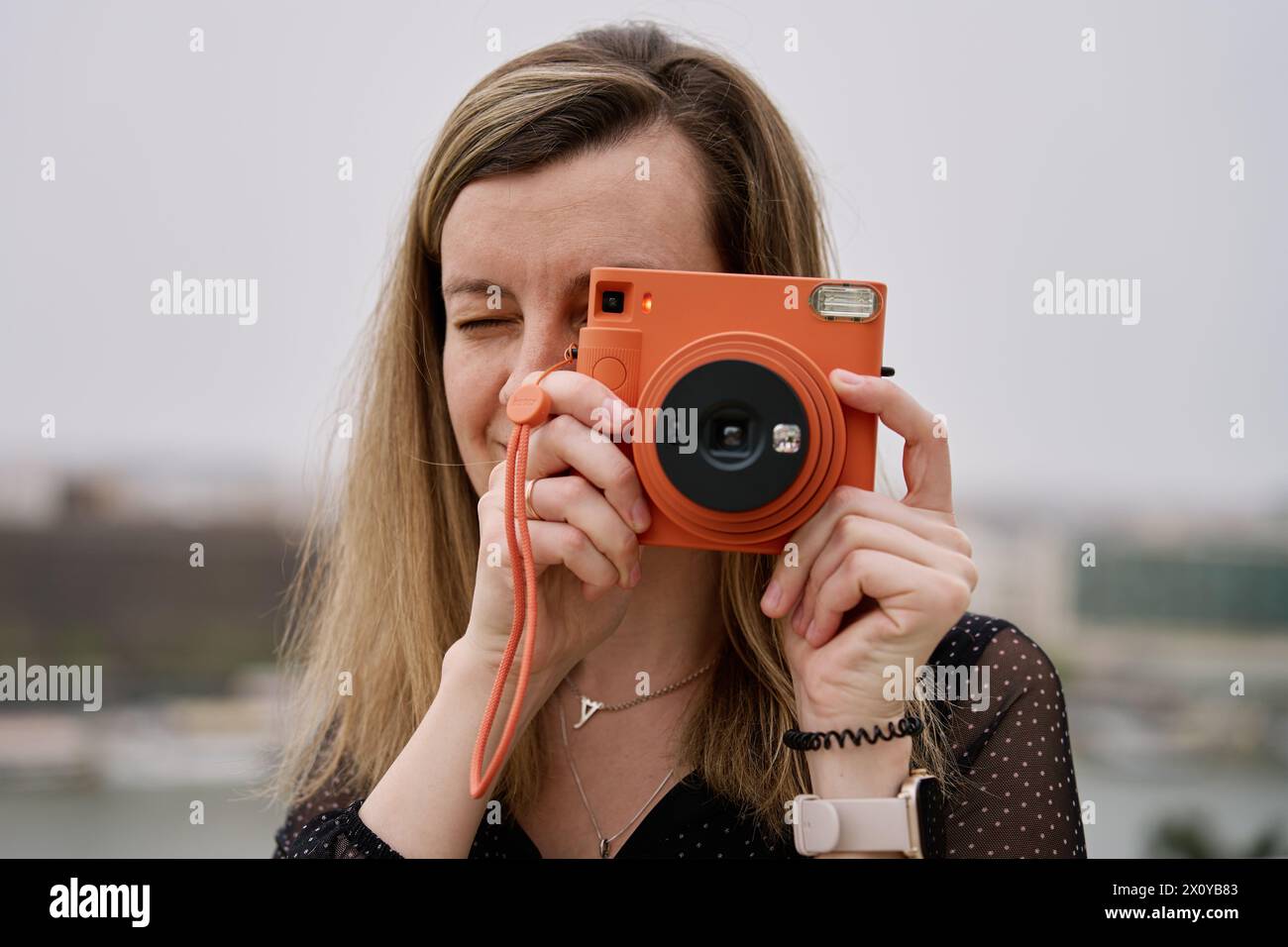 Woman taking picture using orange instant camera. Tourist captures ...