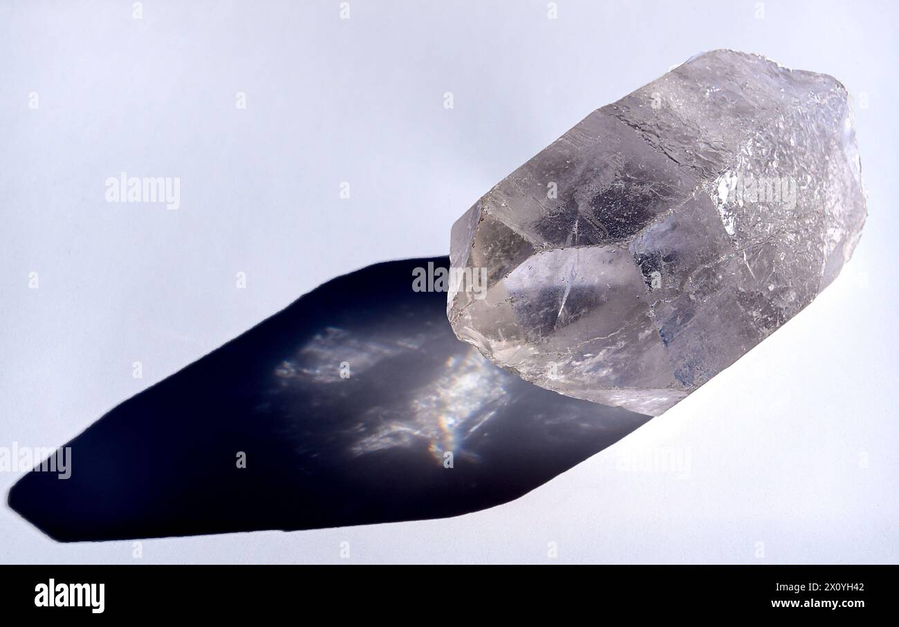 Translucent quartz mineral casts a black and white shadow on a white ...
