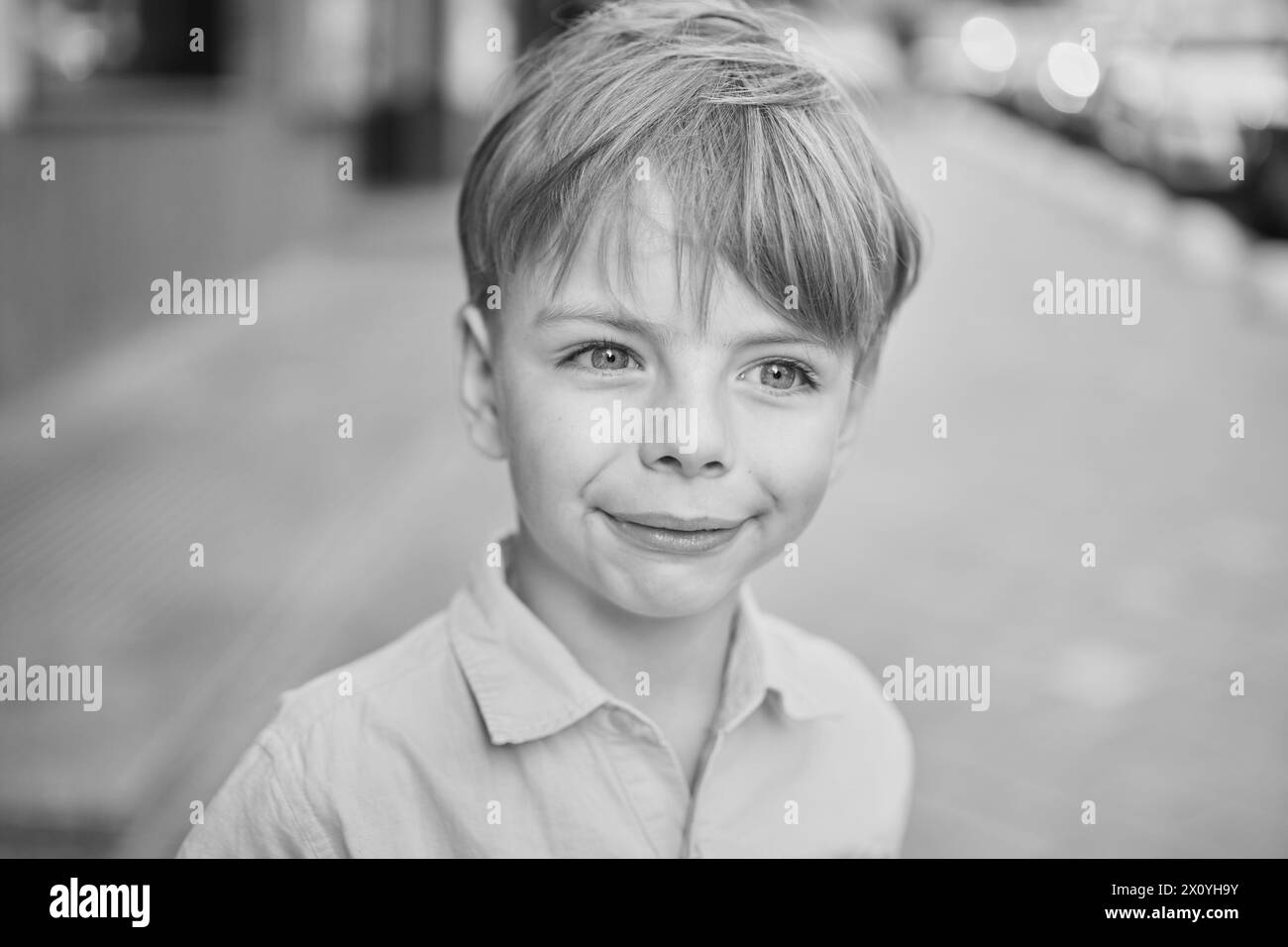 Handsome smiling little boy on the sunny urban background . Close-up ...
