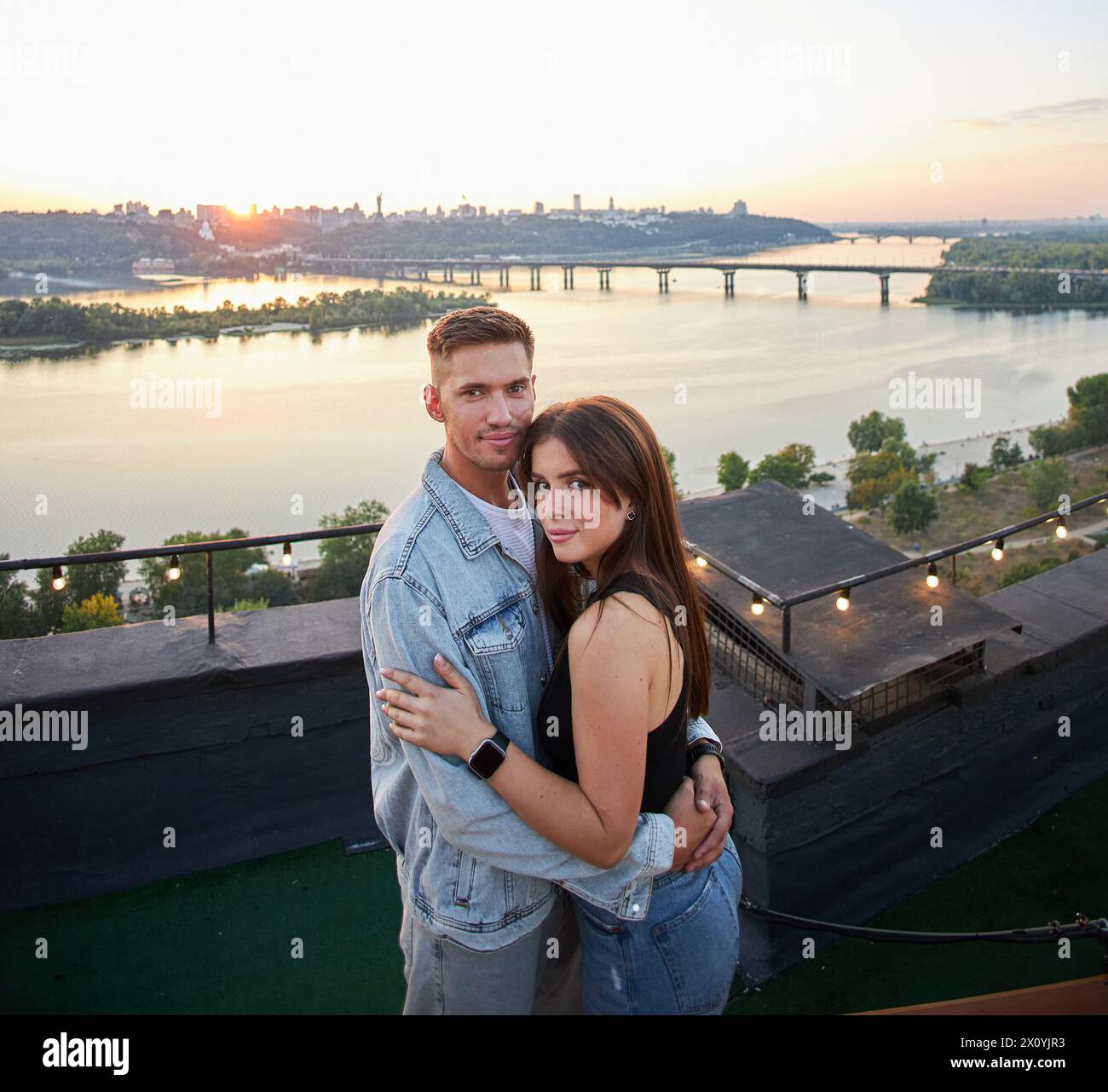 A young couple kisses and embraces during a romantic rooftop date, with ...