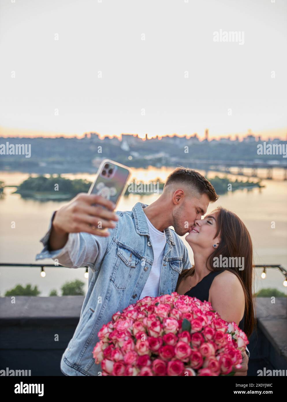A young man surprises his beloved with a vast bouquet of roses as they ...