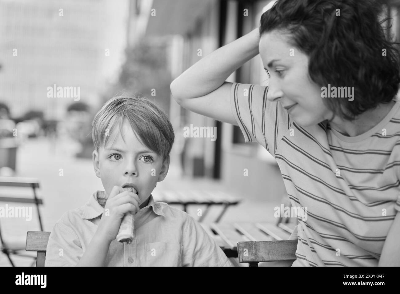 Young mother and her son having sweets in outdoor restaurant on summer ...