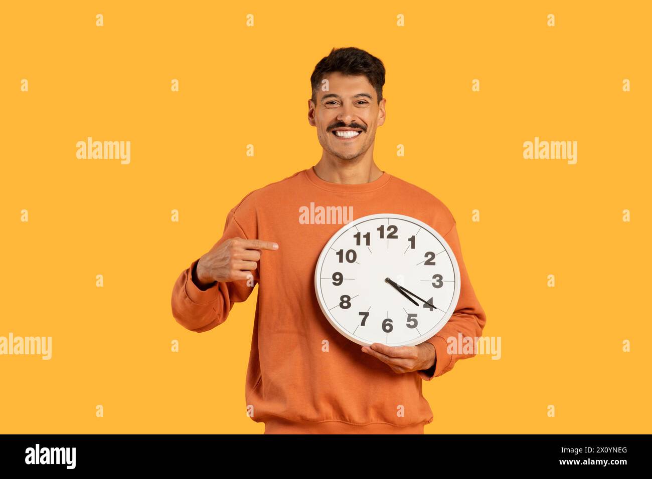 Happy guy with clock showing punctuality on yellow Stock Photo - Alamy