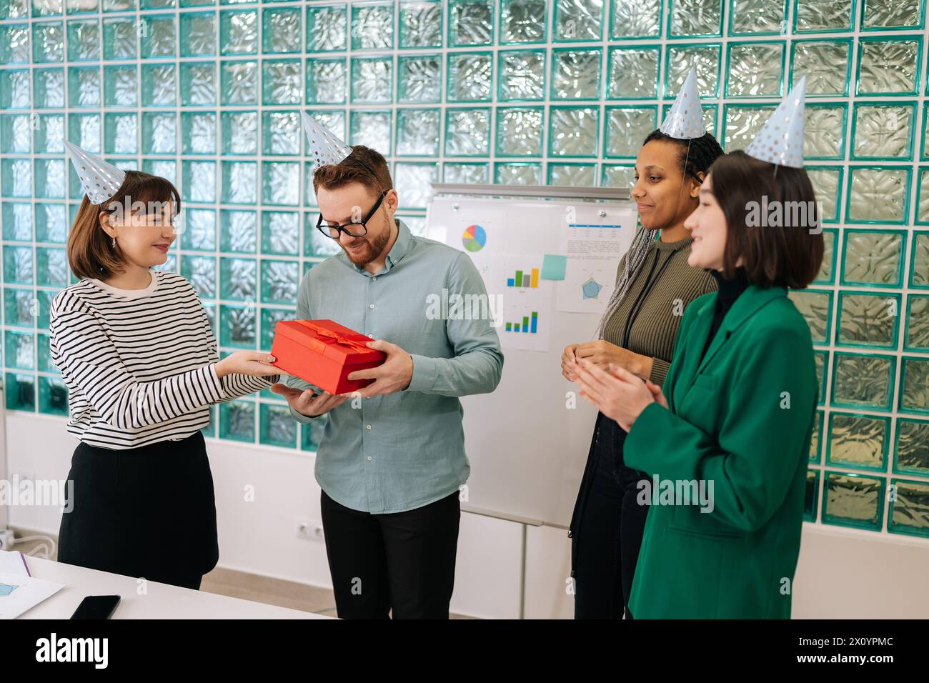 Wide shot business team of office employees in festive caps in modern ...