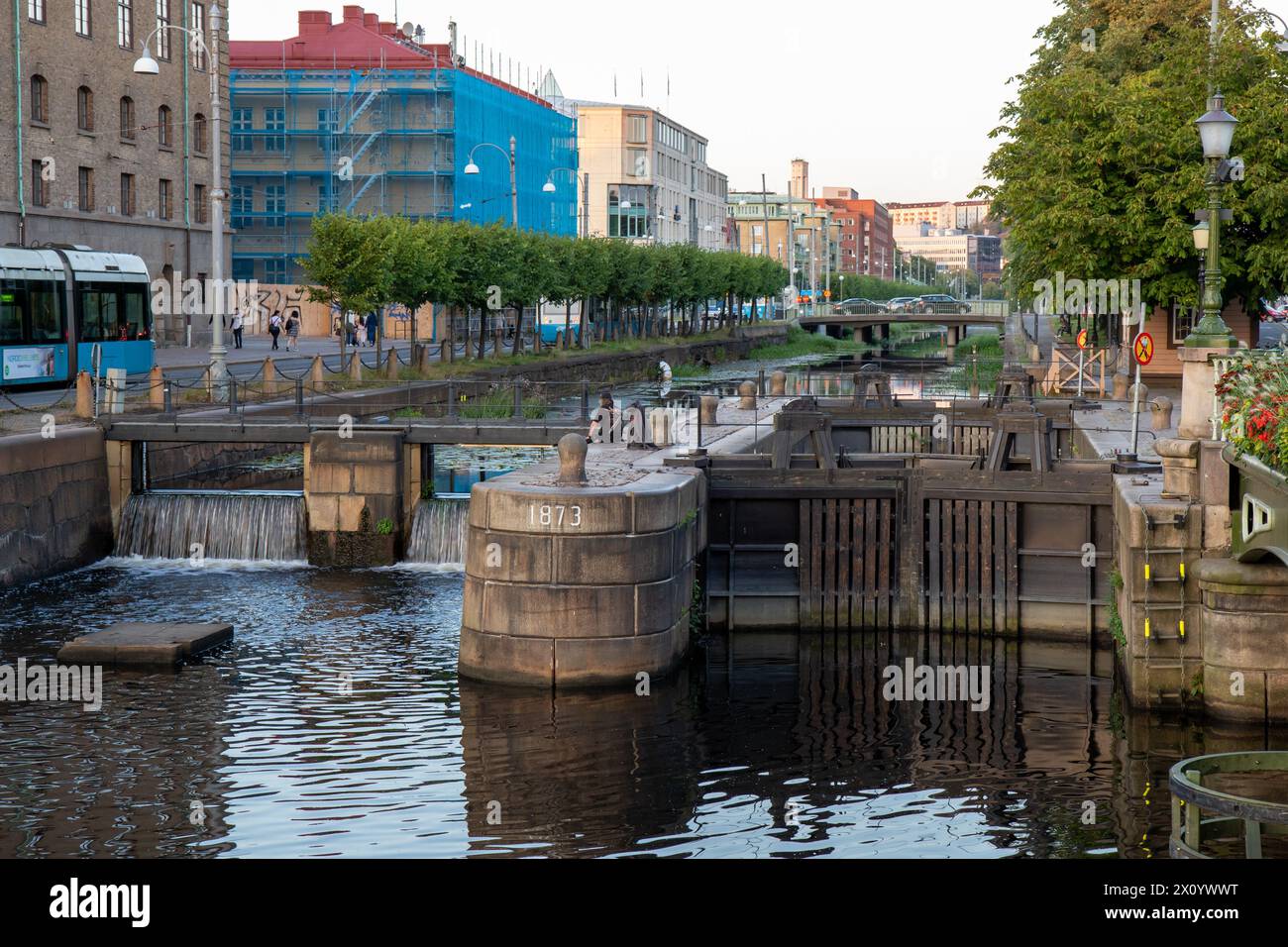 Canal with dam hatches and bridge in background. Buildings and a tram ...