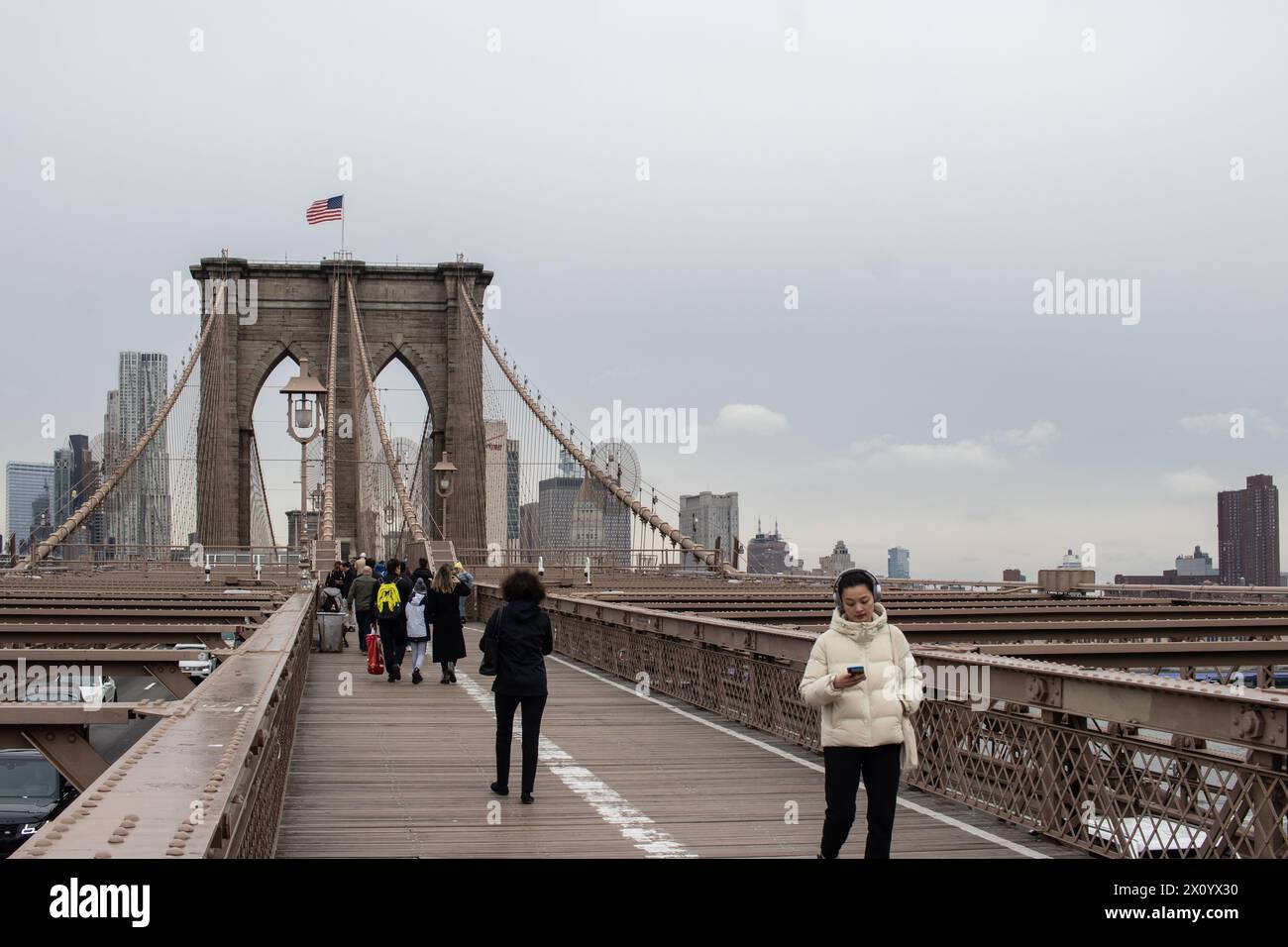 People walking on Brooklyn bridge with one girl checking her phone ...