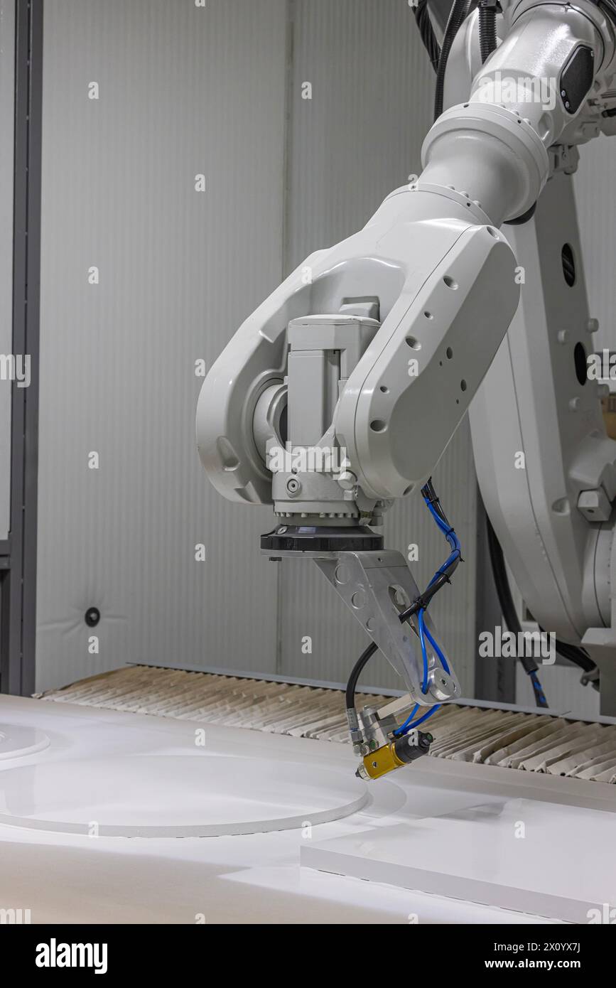 Vertical shot of a robot arm painting a wooden chair in a furniture ...