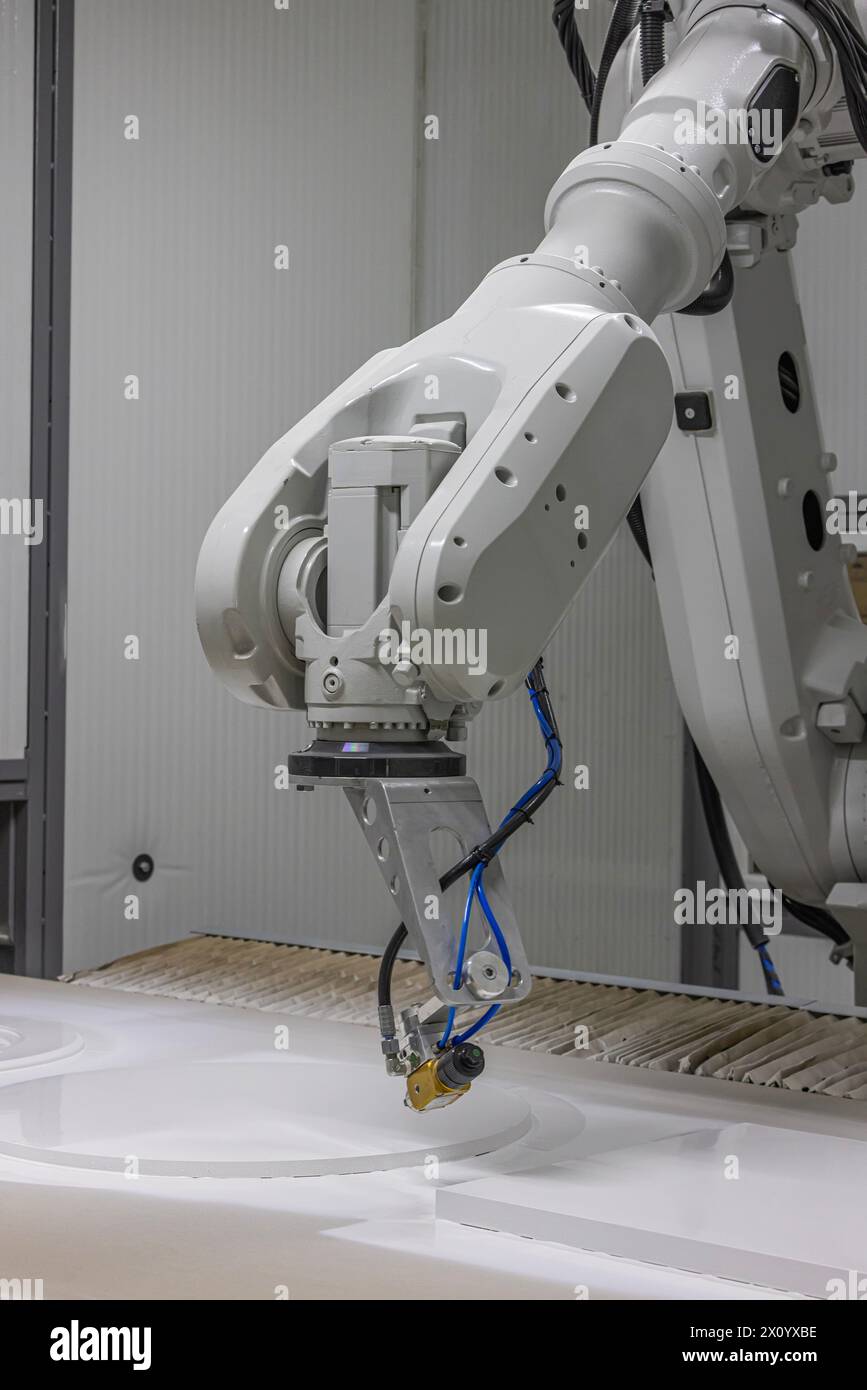 Vertical shot of a robot arm painting a wooden chair in a furniture ...