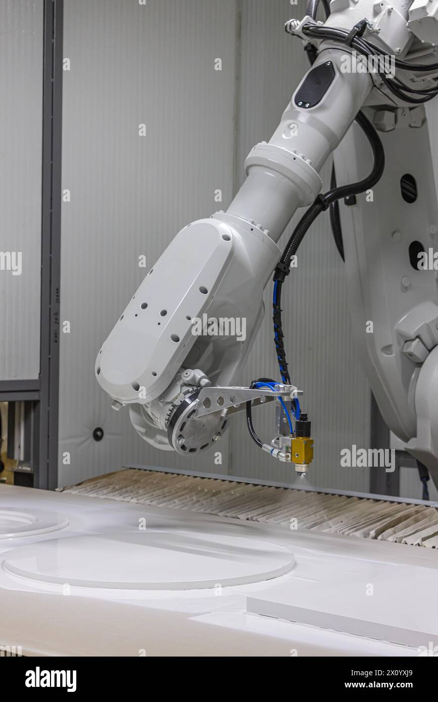 Vertical shot of a robot arm painting a wooden chair in a furniture ...