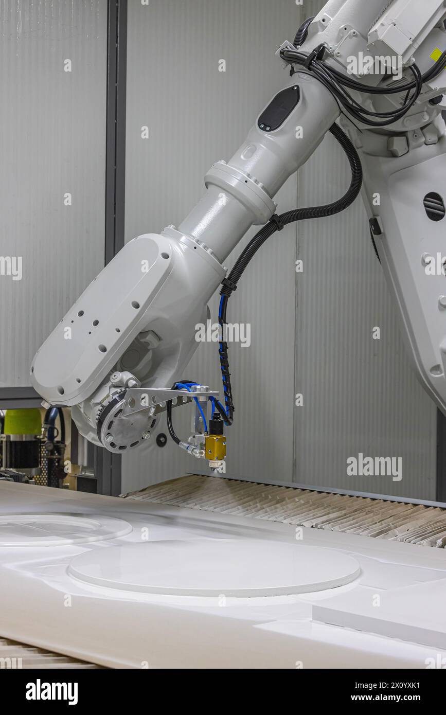 Vertical shot of a robot arm painting a wooden chair in a furniture ...