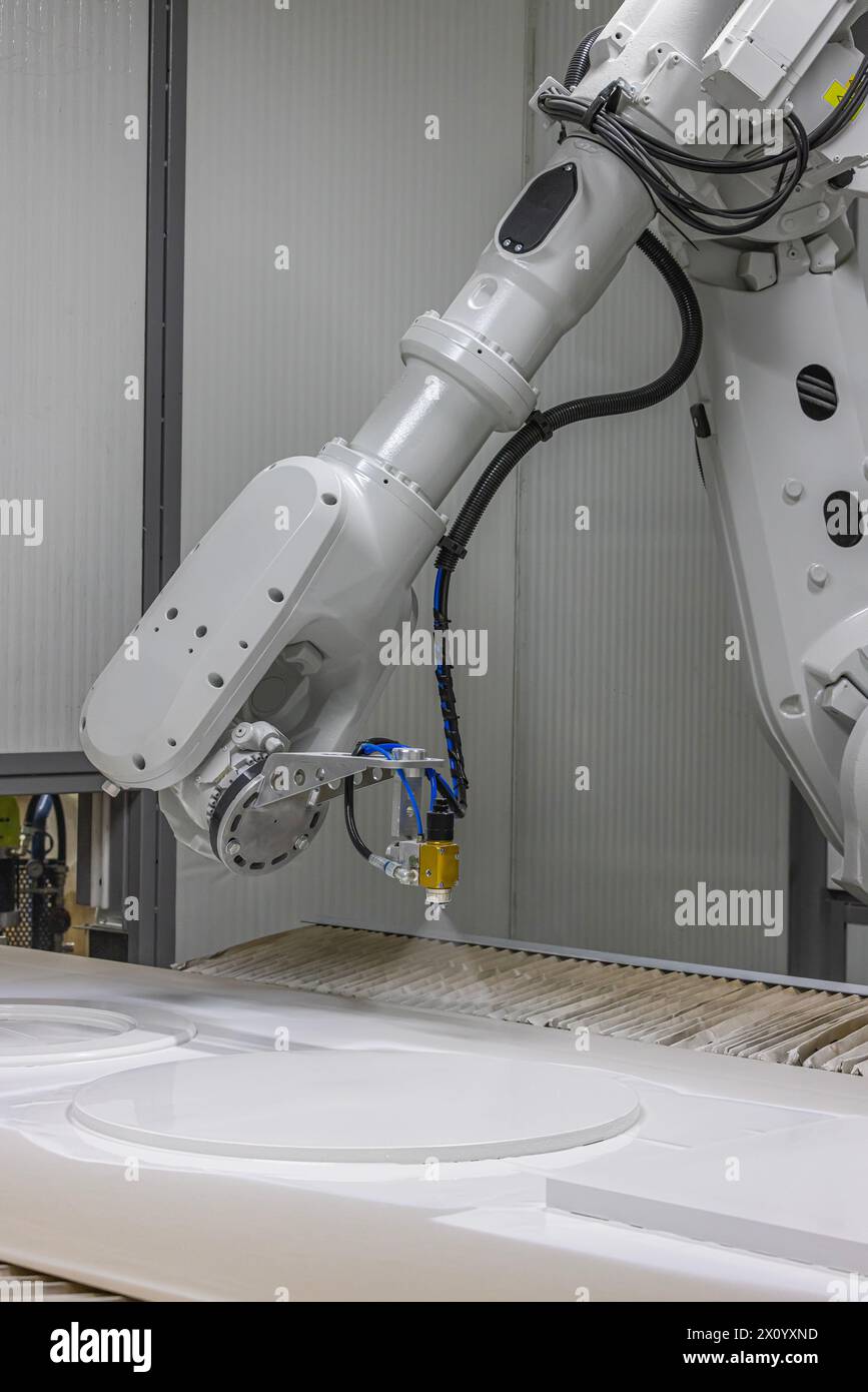 Vertical shot of a robot arm painting a wooden chair in a furniture ...