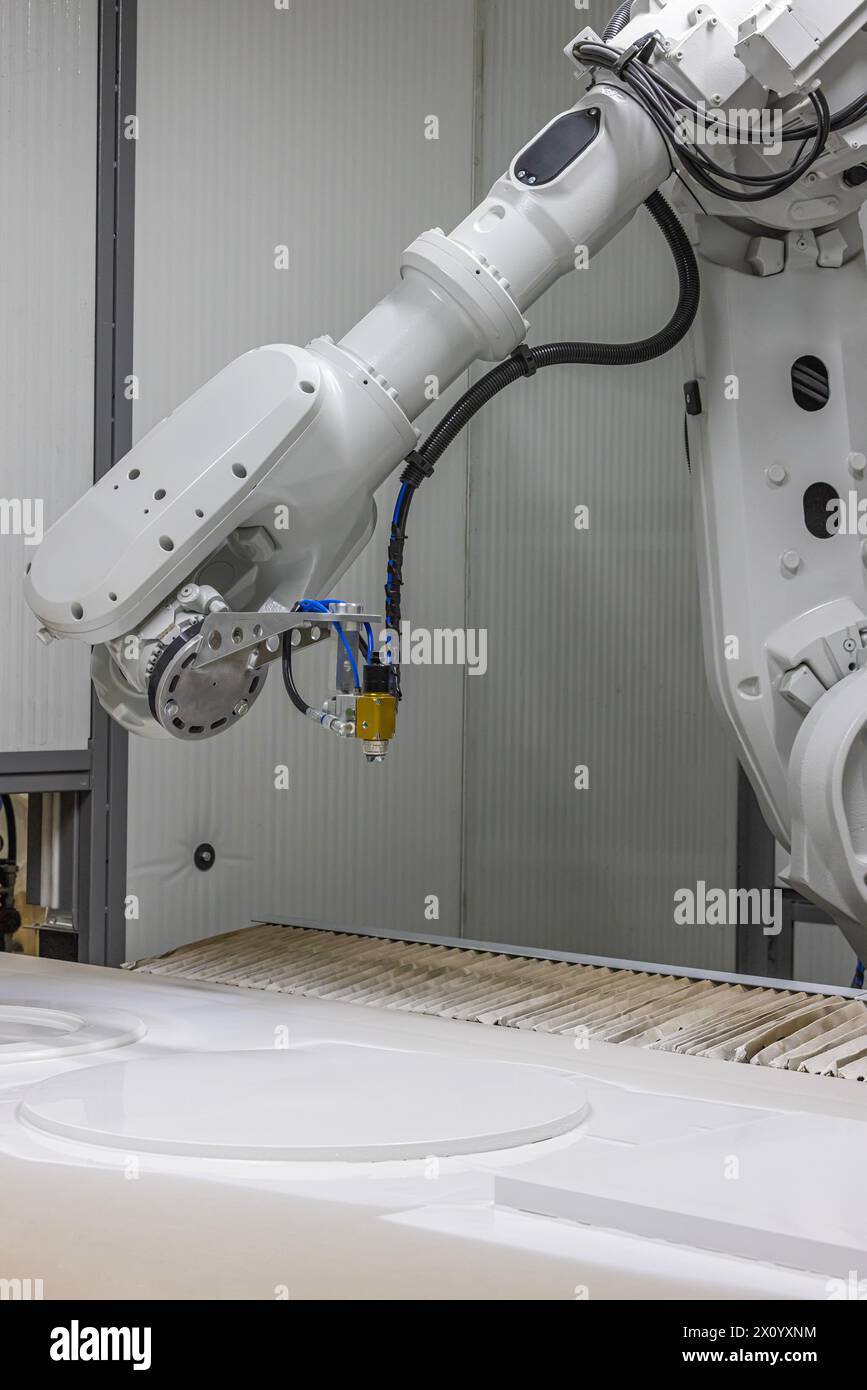 Vertical shot of a robot arm painting a wooden chair in a furniture ...