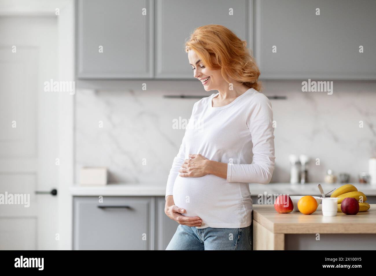 Expecting lady in a bright modern kitchen Stock Photo - Alamy
