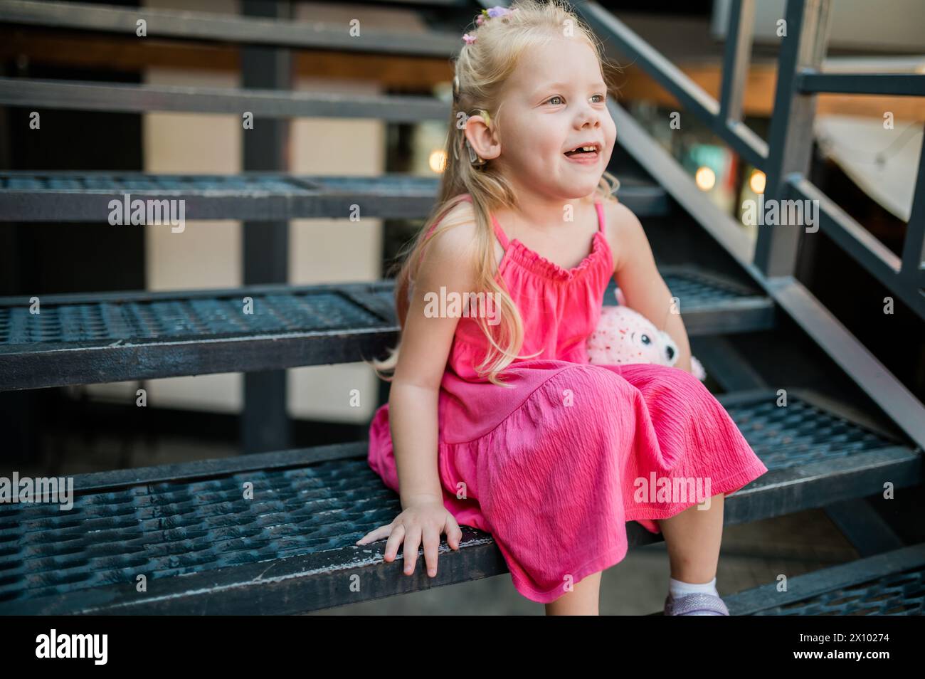 Child girl with hearing aid cochlear implant in pink dress having fun ...