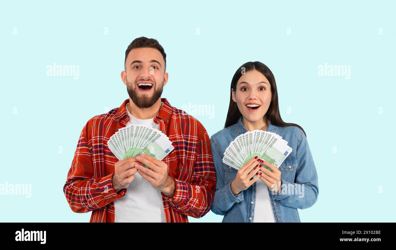 Excited couple holding money fan on blue background Stock Photo - Alamy