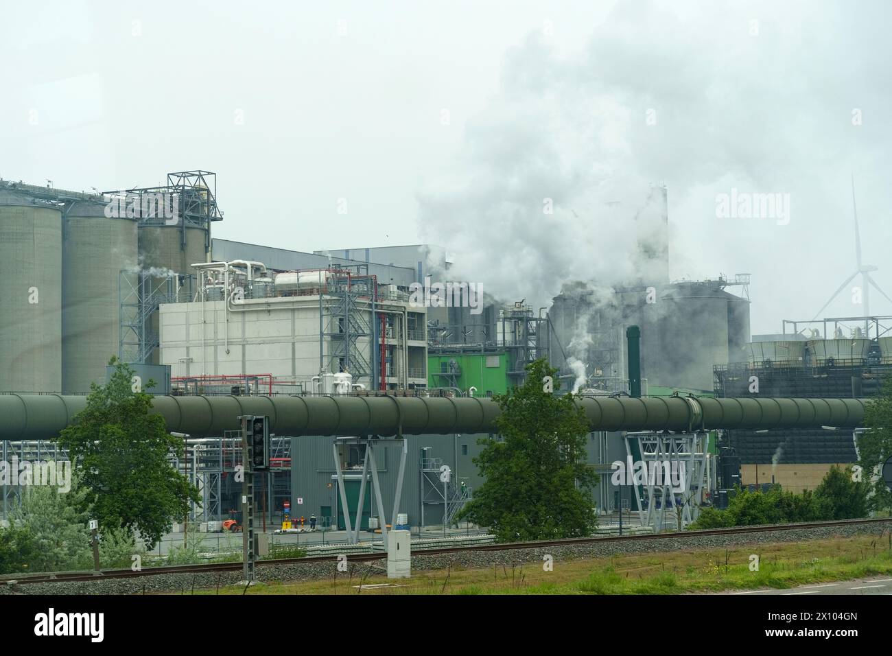 A factory releasing billowing smoke from its tall stacks into the sky ...