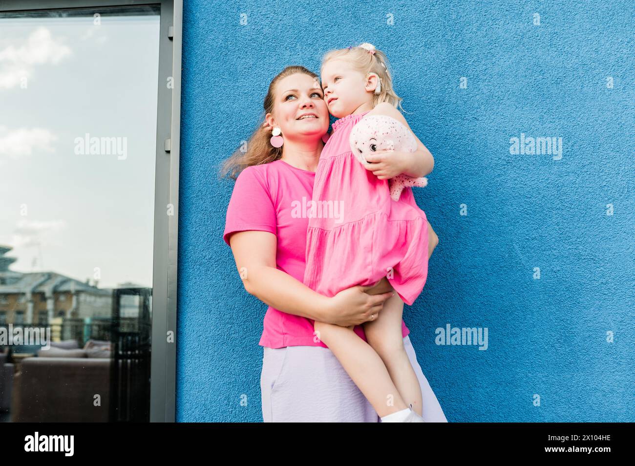 Mother holds and have fun her child with hearing aids and cochlear ...
