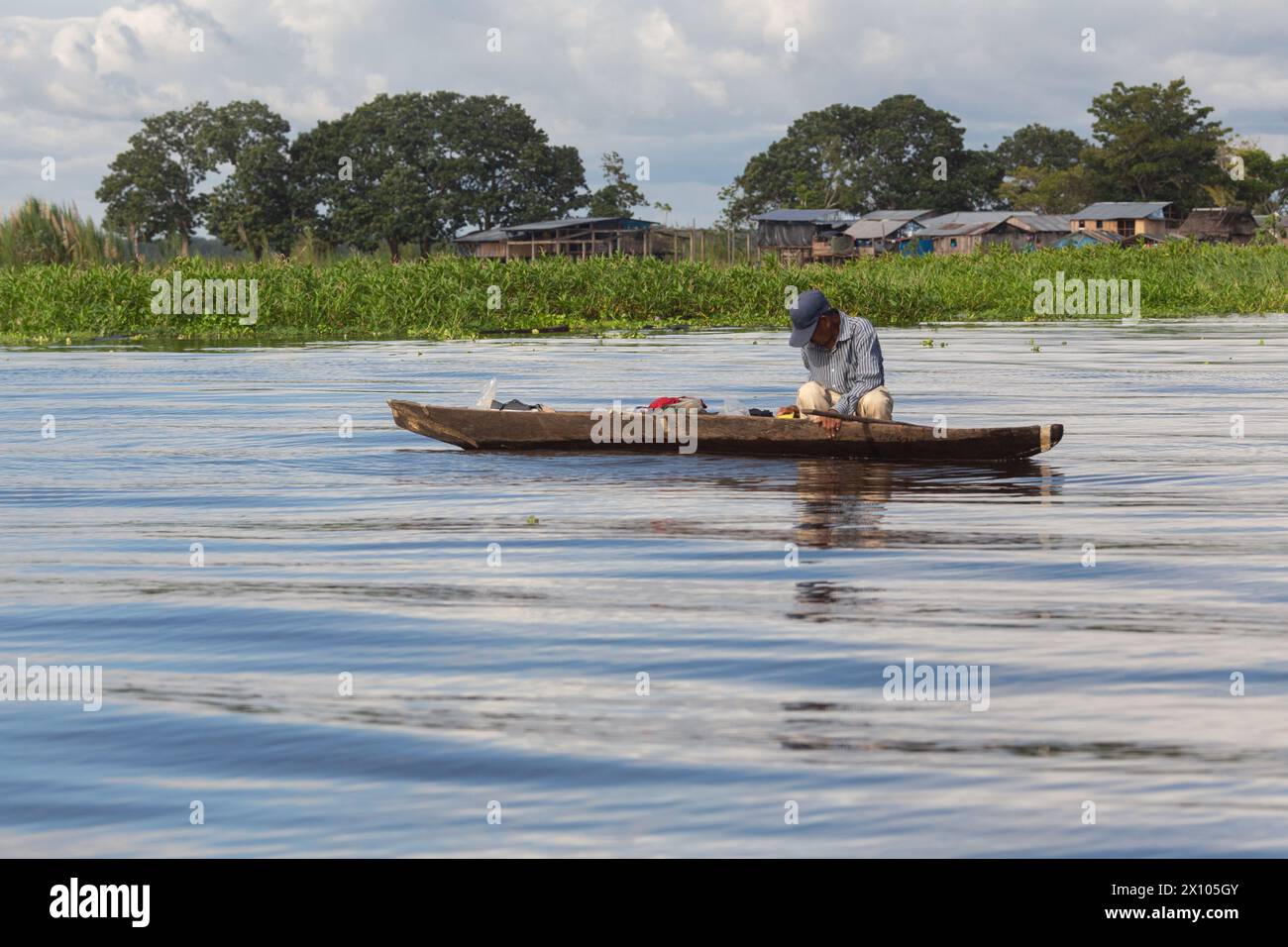 A fisherman in a dugout canoe floats on the water outside of Iquitos ...