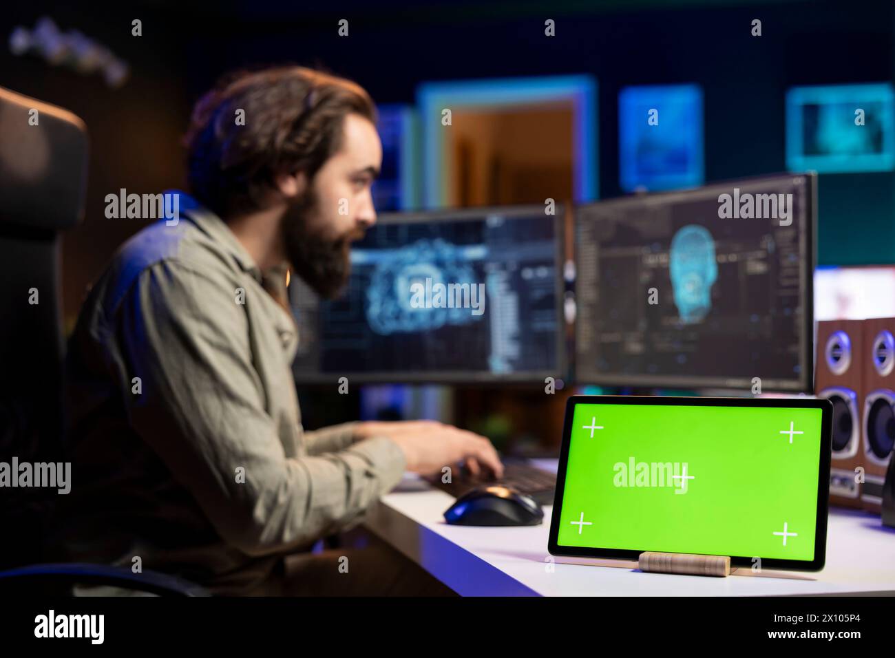 Focus on green screen device next to man in blurry background updating artificial intelligence ...
