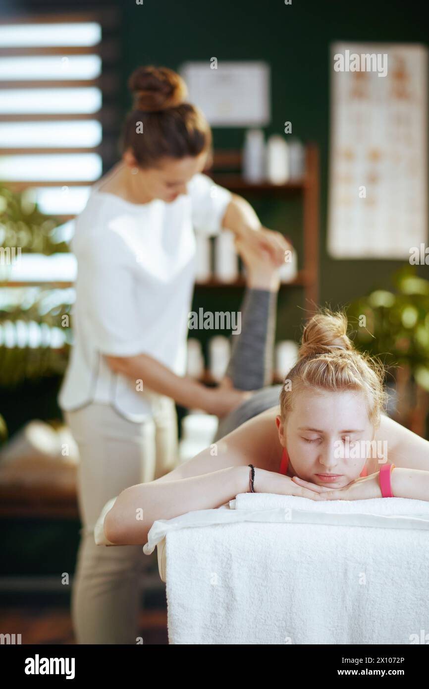 Healthcare time. massage therapist woman in massage cabinet with teenage client making massage ...