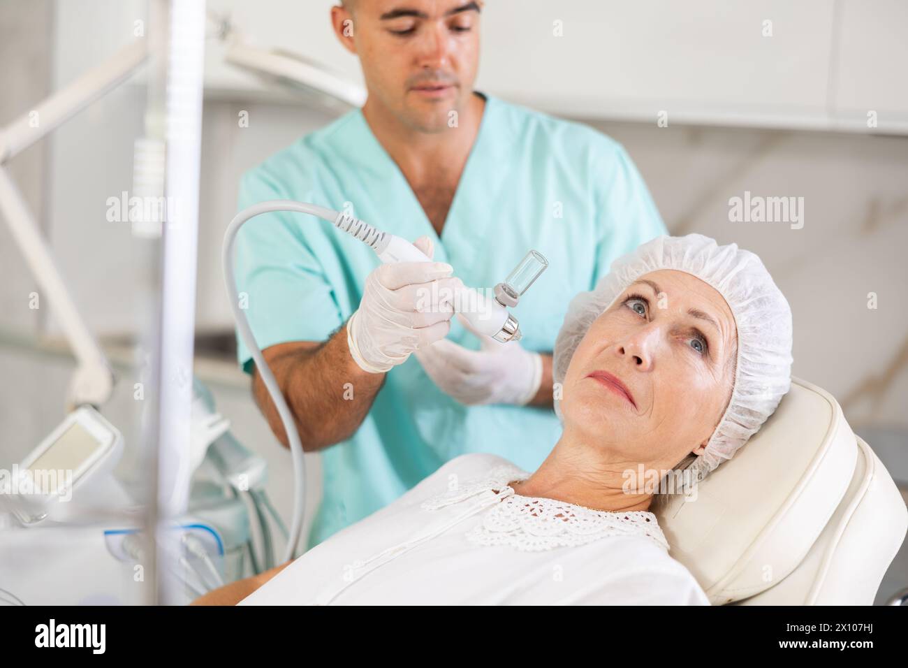 Male dermatologist performing cosmetology procedure for elderly woman ...