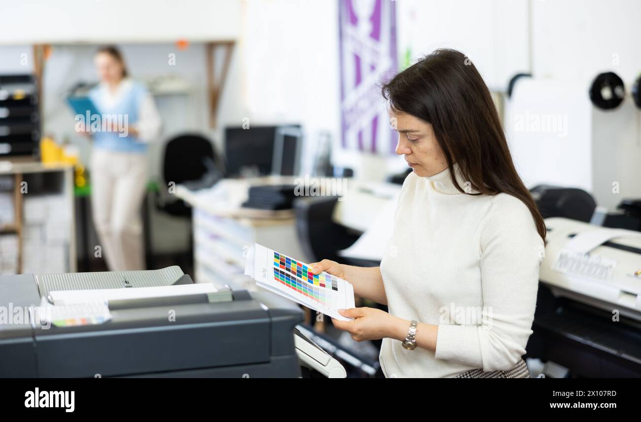 Printing office manager looking at colour test page for printer Stock ...