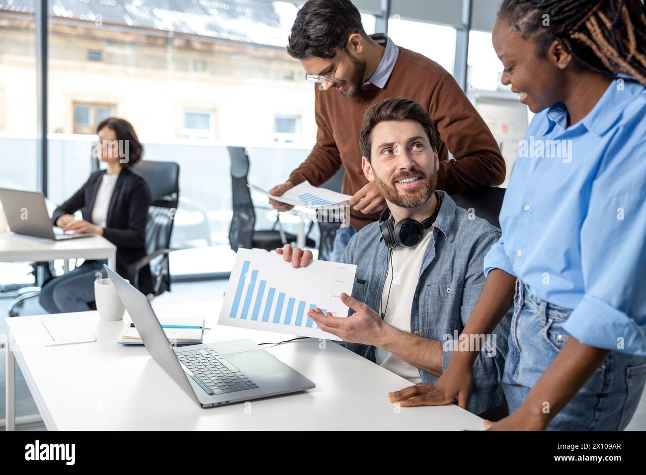 Group of professionals collaborating and using laptop in coworking ...