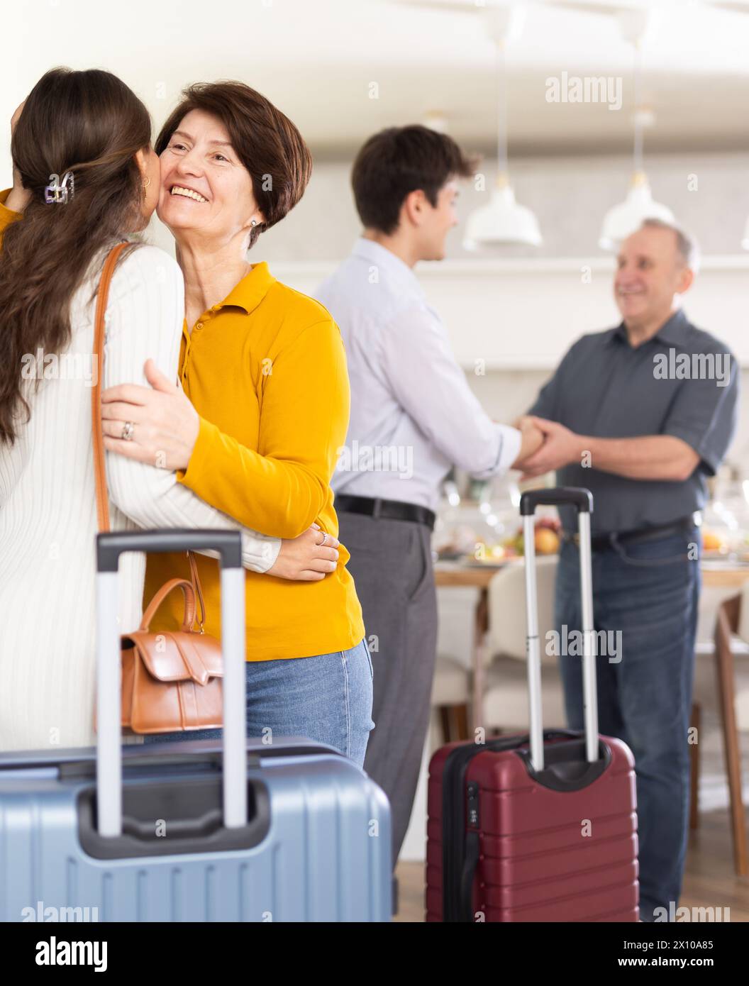 Friendly mother-in-law greeting visiting daughter-in-law with kiss ...
