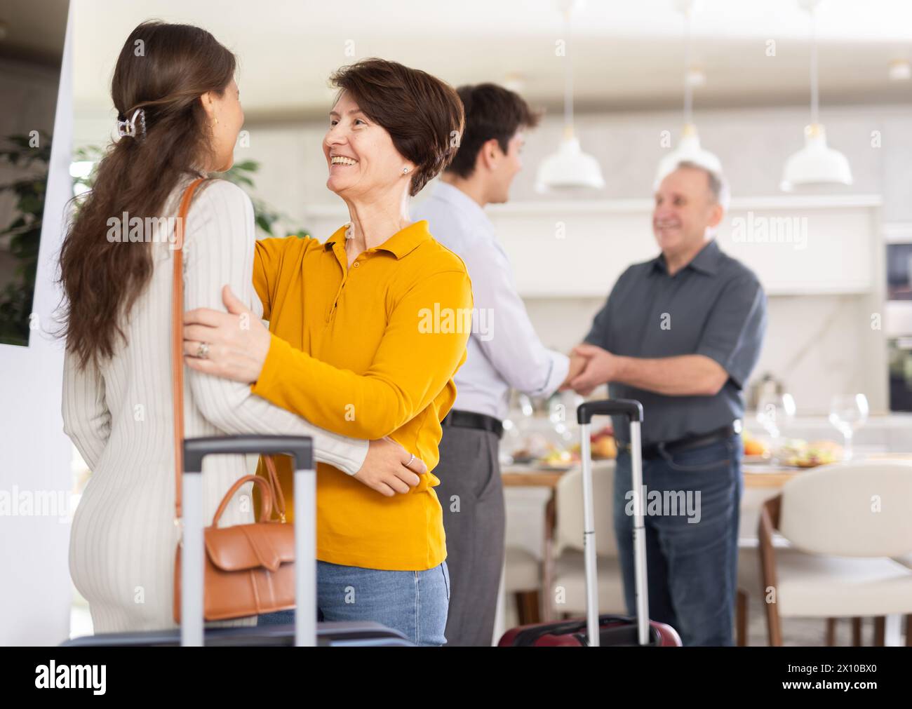 Young girl with suitcase coming back home and hugging mother at door ...