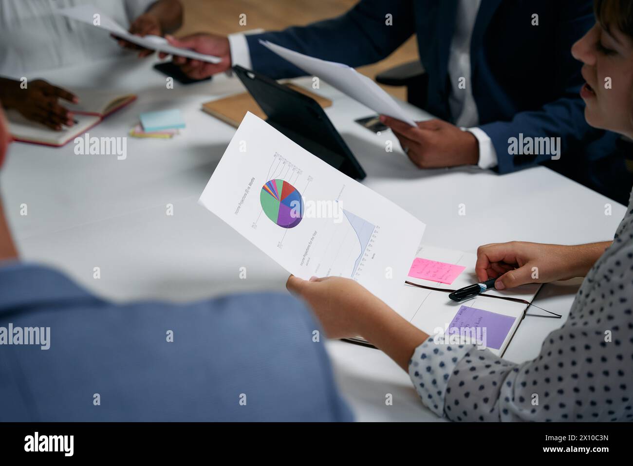 Four multiracial adults reviewing document with graph during business ...