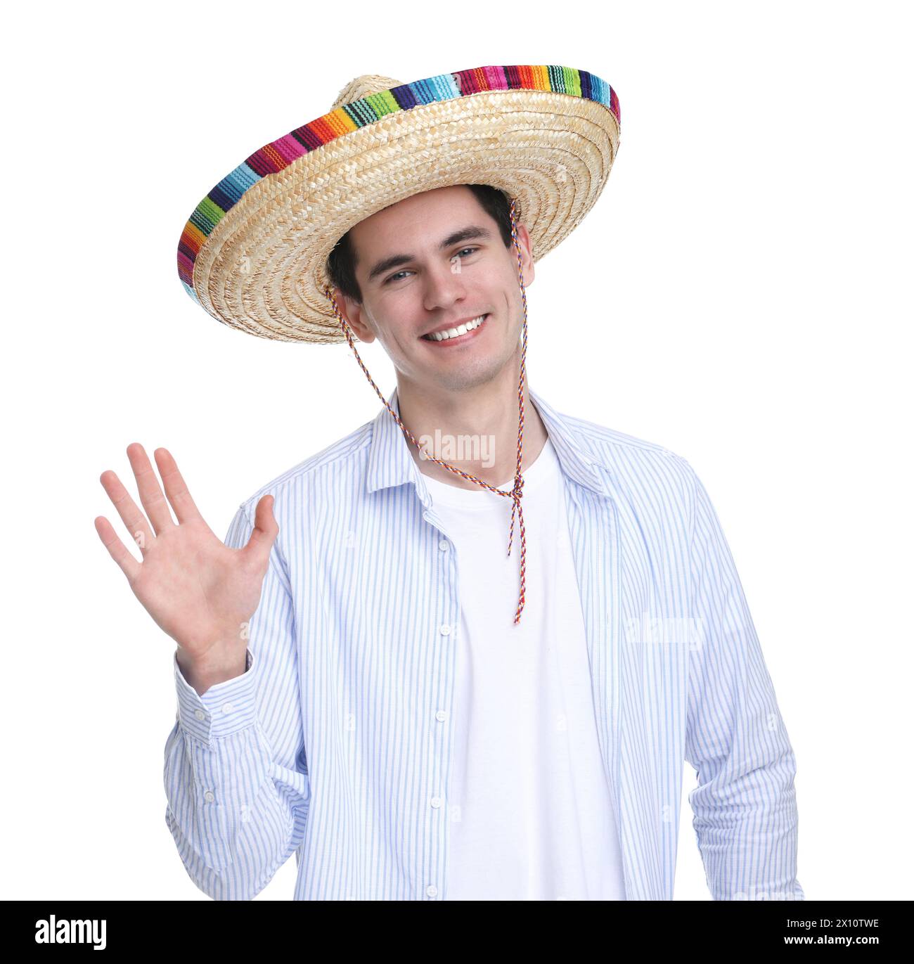 Young man in Mexican sombrero hat waving hello on white background ...