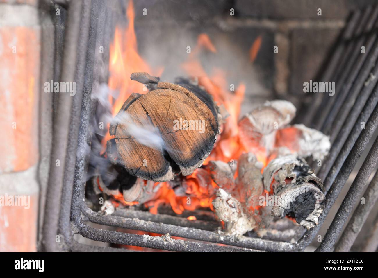 A pile of wood is burning in a fire pit. The fire is hot and the smoke ...