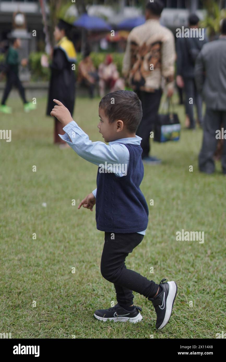 A boy wearing a blue shirt and black shoes is running with one hand ...