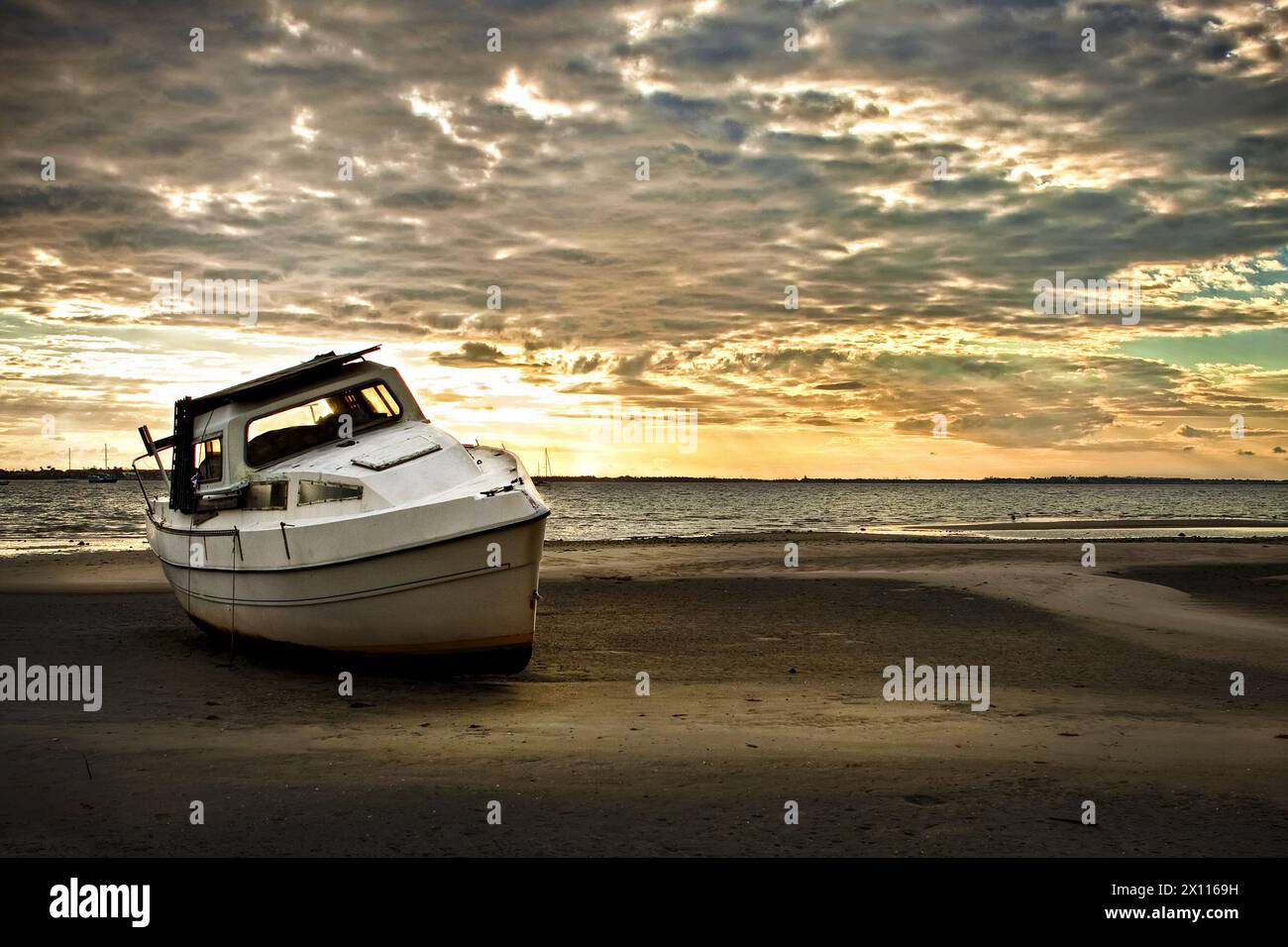 boat stranded on beach after storm sunset dramatic sky Stock Photo - Alamy