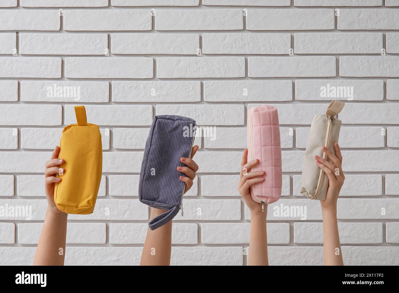 Child's hands with colorful pencil cases on brick background Stock ...
