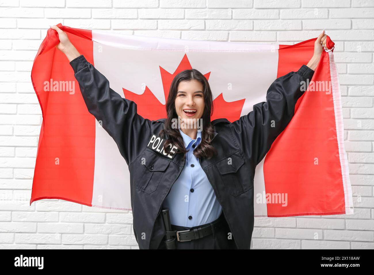 Female police officer with flag of Canada on white brick background ...