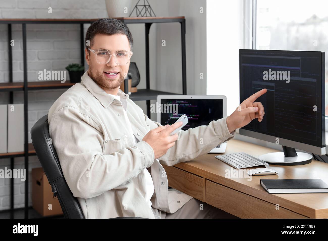 Portrait of male programmer pointing at computer screen in office Stock Photo - Alamy