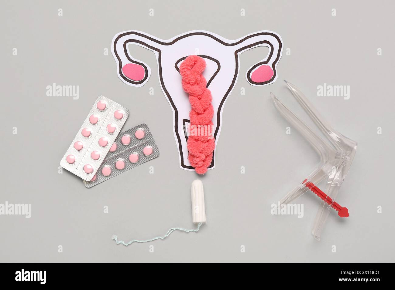 Paper uterus with pills, tampon and gynecological speculum on grey ...