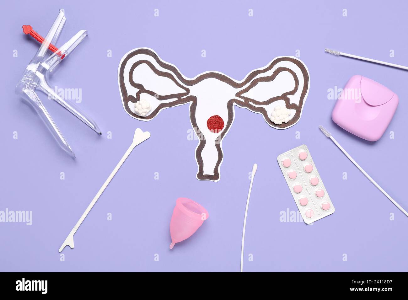 Paper uterus with gynecological speculum, pills, menstrual cup and pap ...