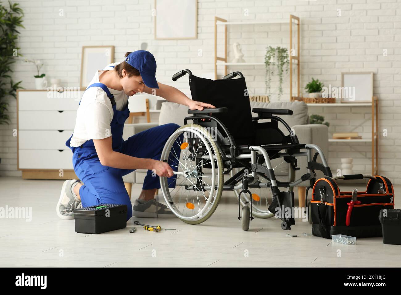 Male worker with wrench repairing wheelchair in room Stock Photo - Alamy