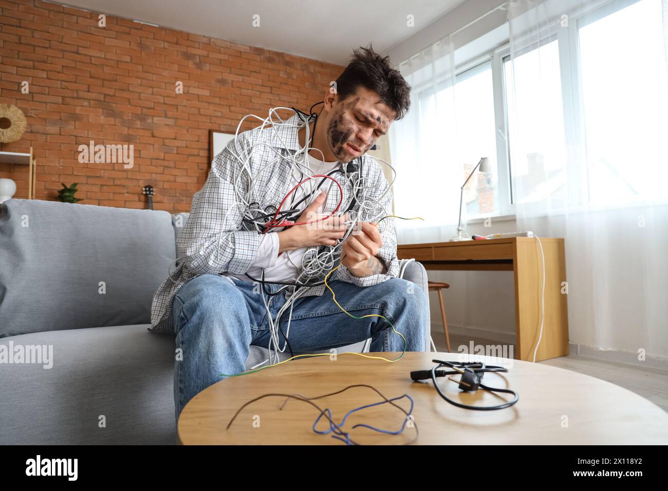 Electrocuted young man with burnt face and wires sitting on sofa at ...