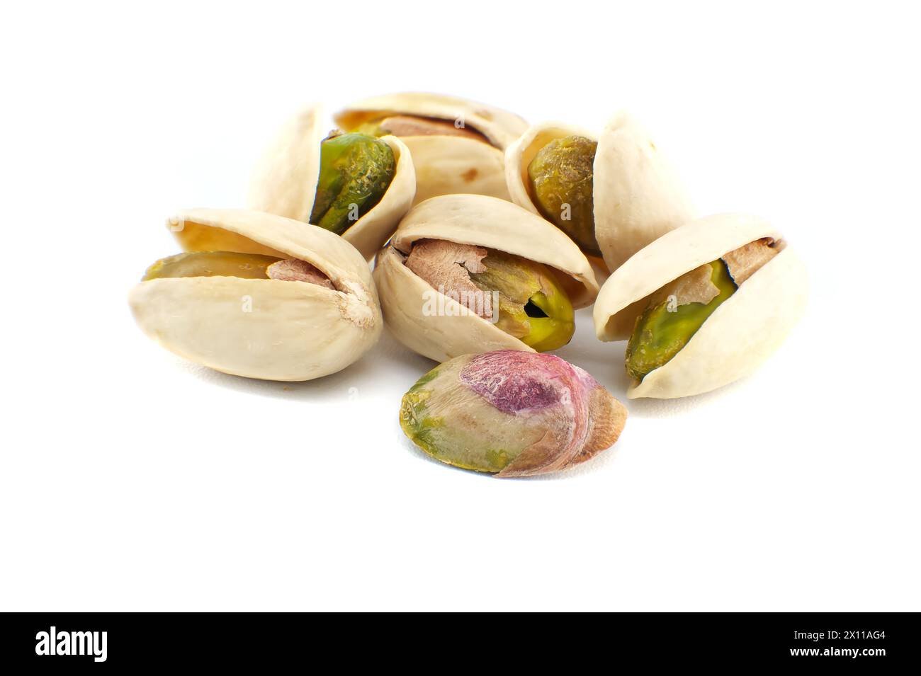 Pistachios in-shell and others peeled exposing the green nuts inside ...