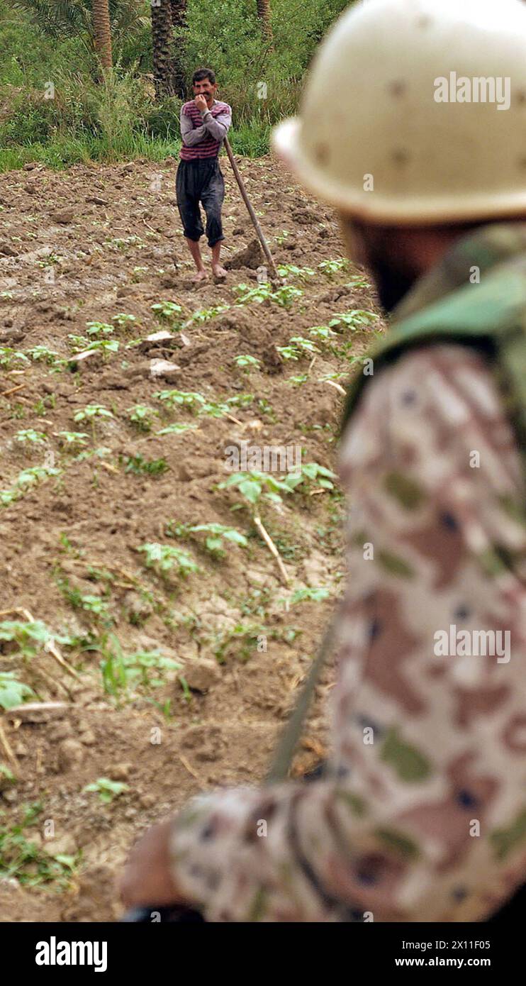 Original Caption: A farmer takes a break to watch a soldier from the ...