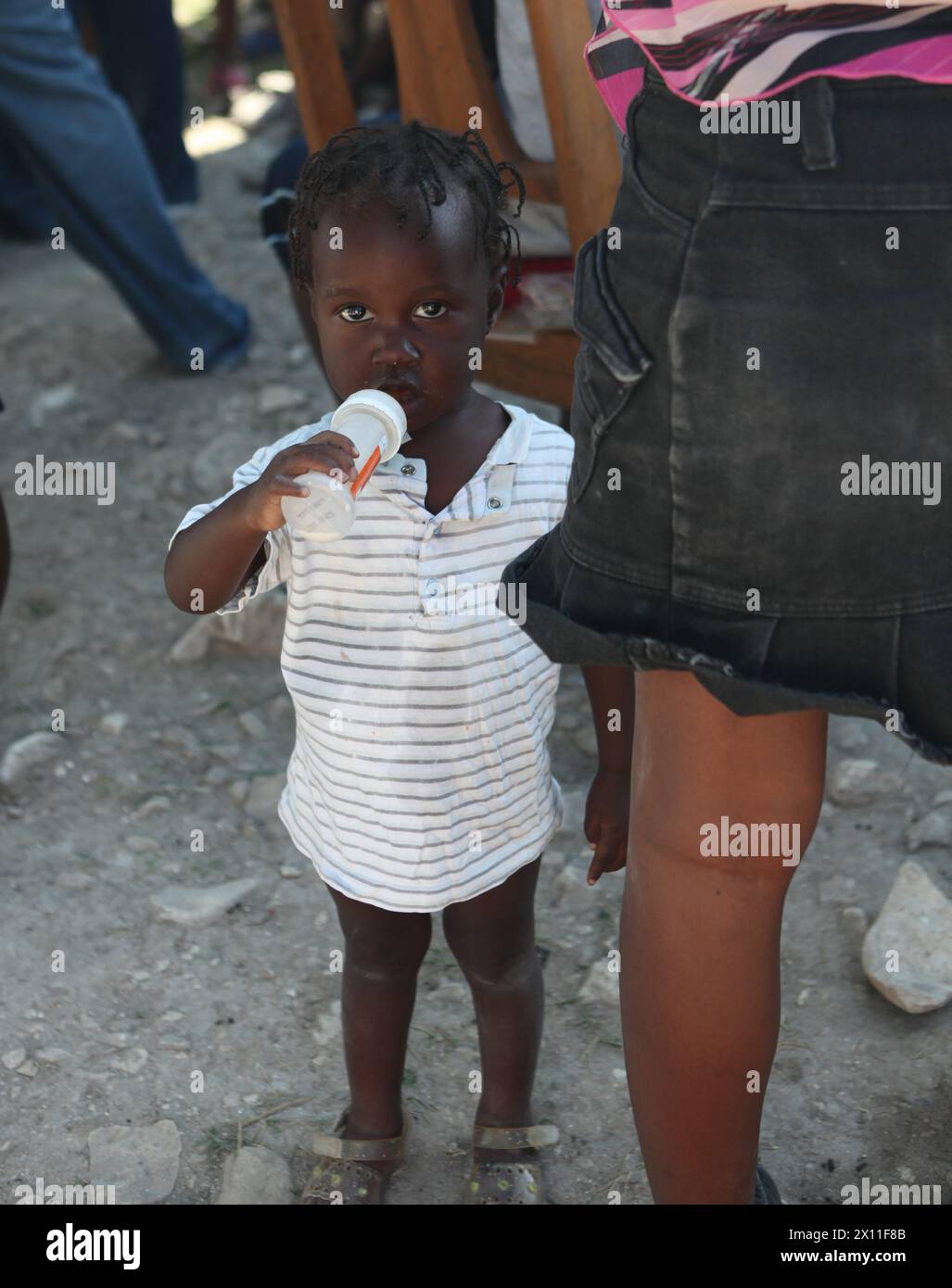 A Haitian child drinks from a bottle given out by corpsmen with ...