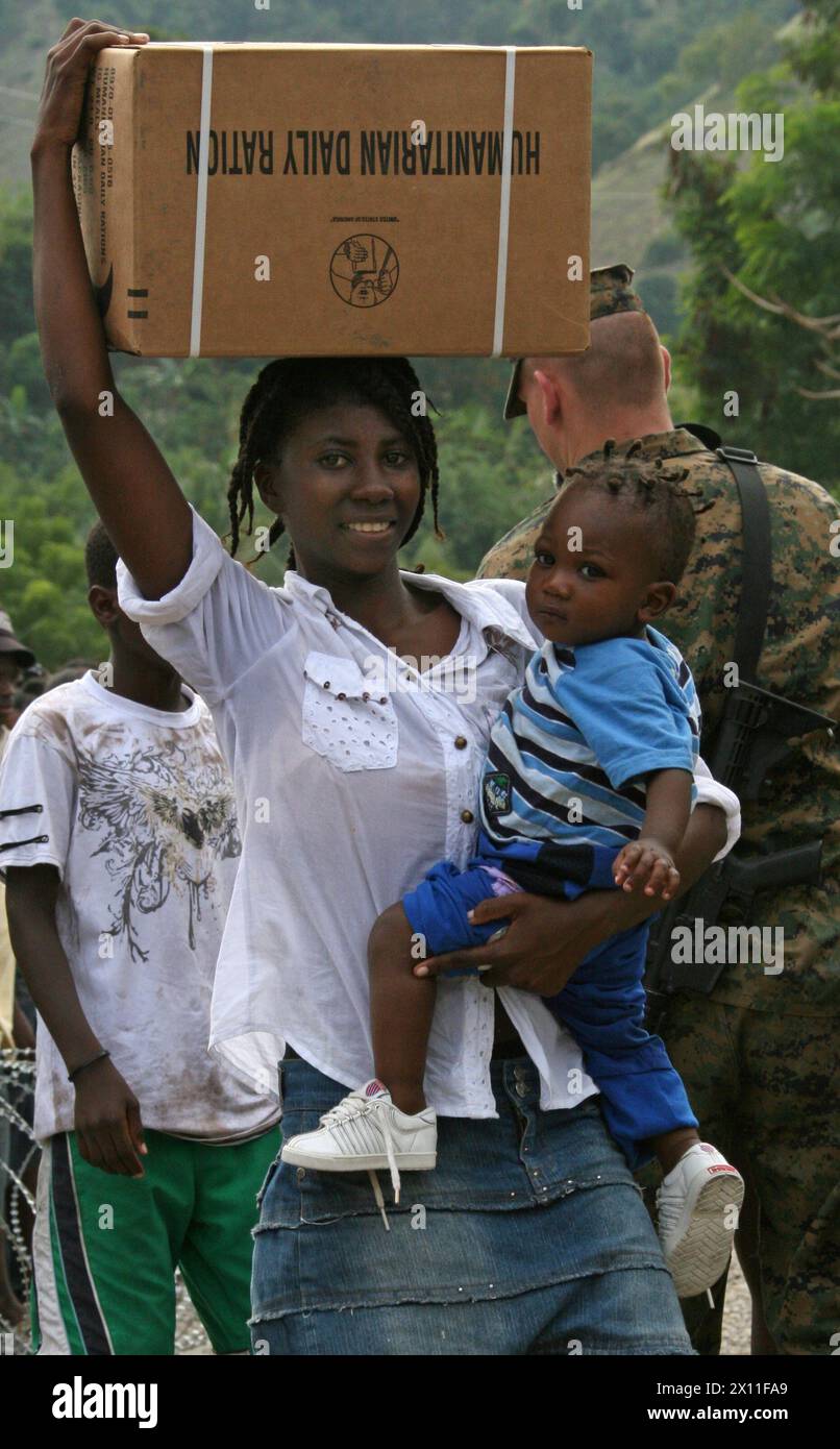 A Haitian woman with a child carries her rations away with a smile from ...